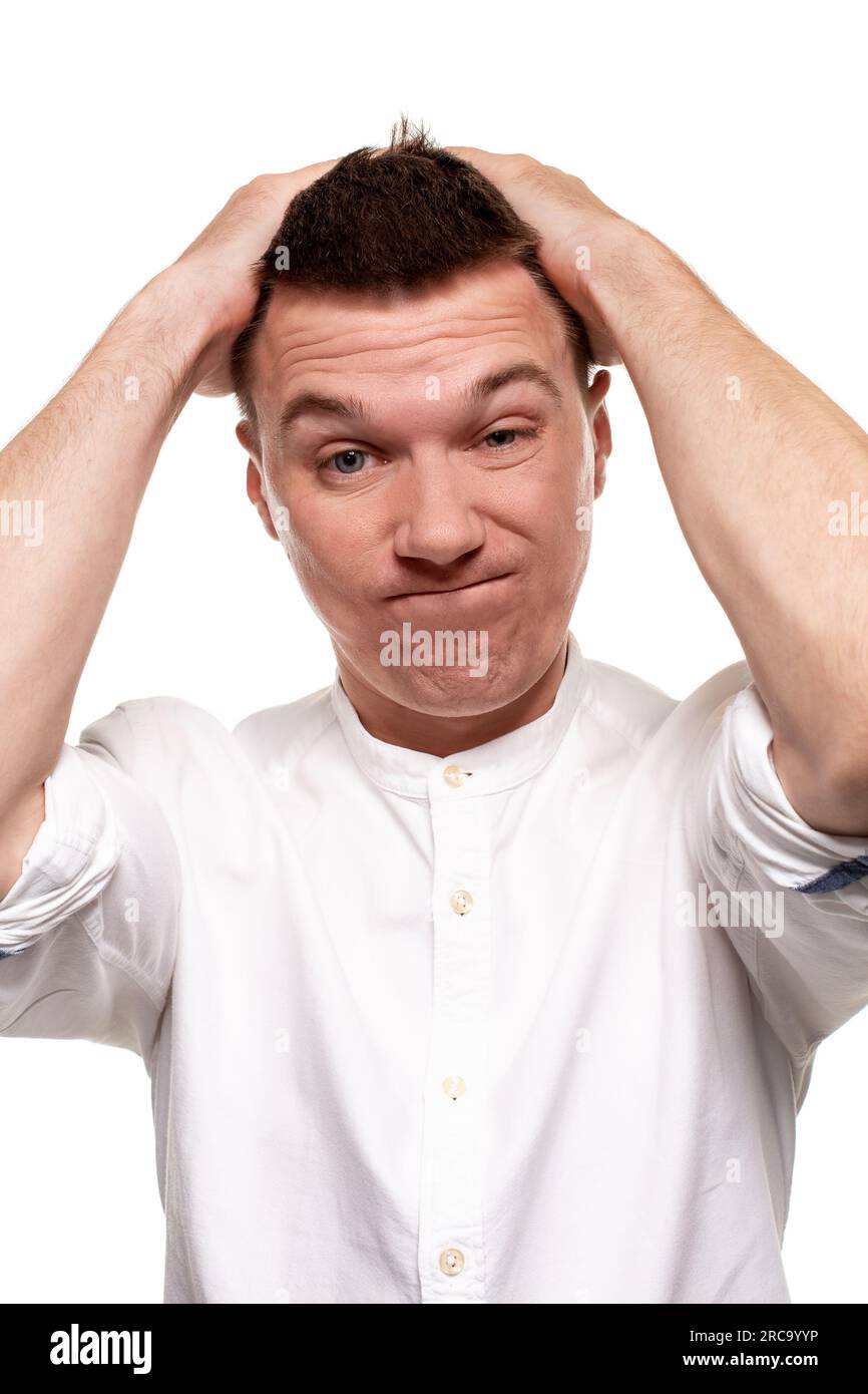 Charming handsome young man in a white shirt is making faces, while ...