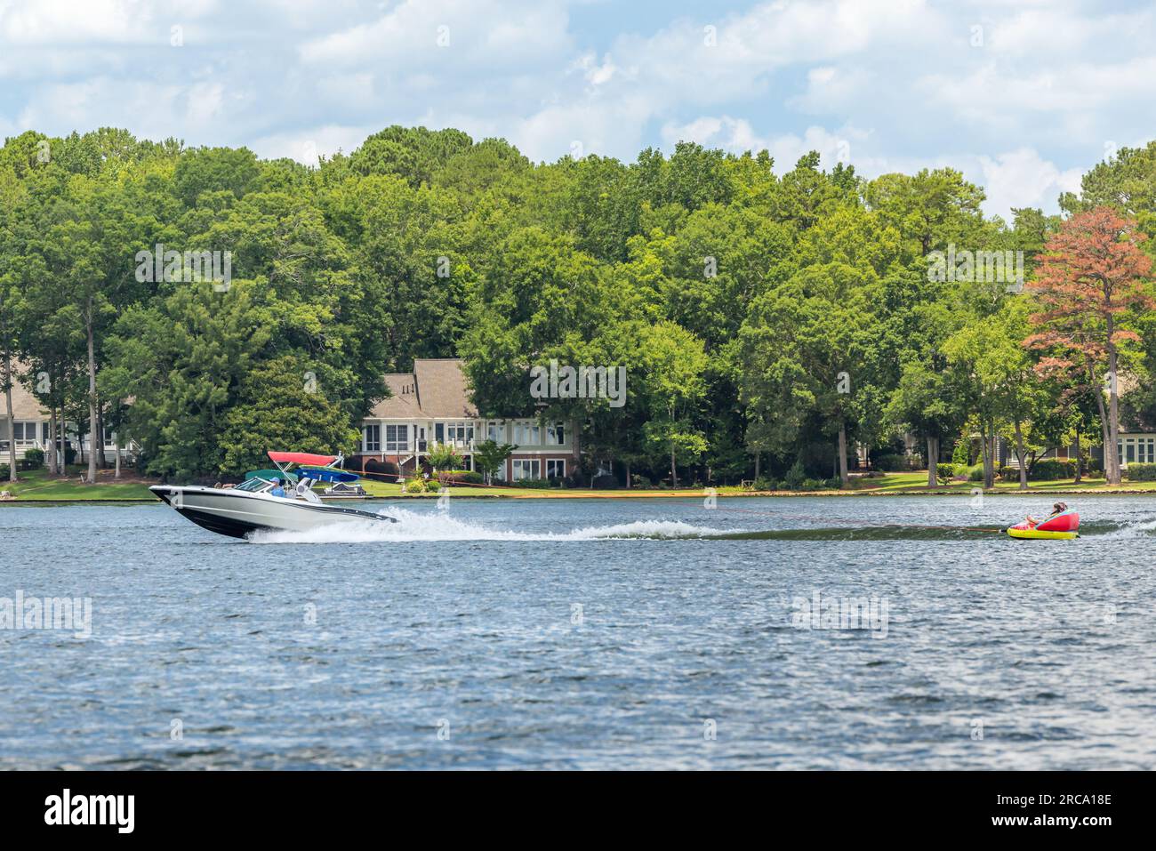 Power boat pulling inflatable tube float raft on lake. Family on a ski ...