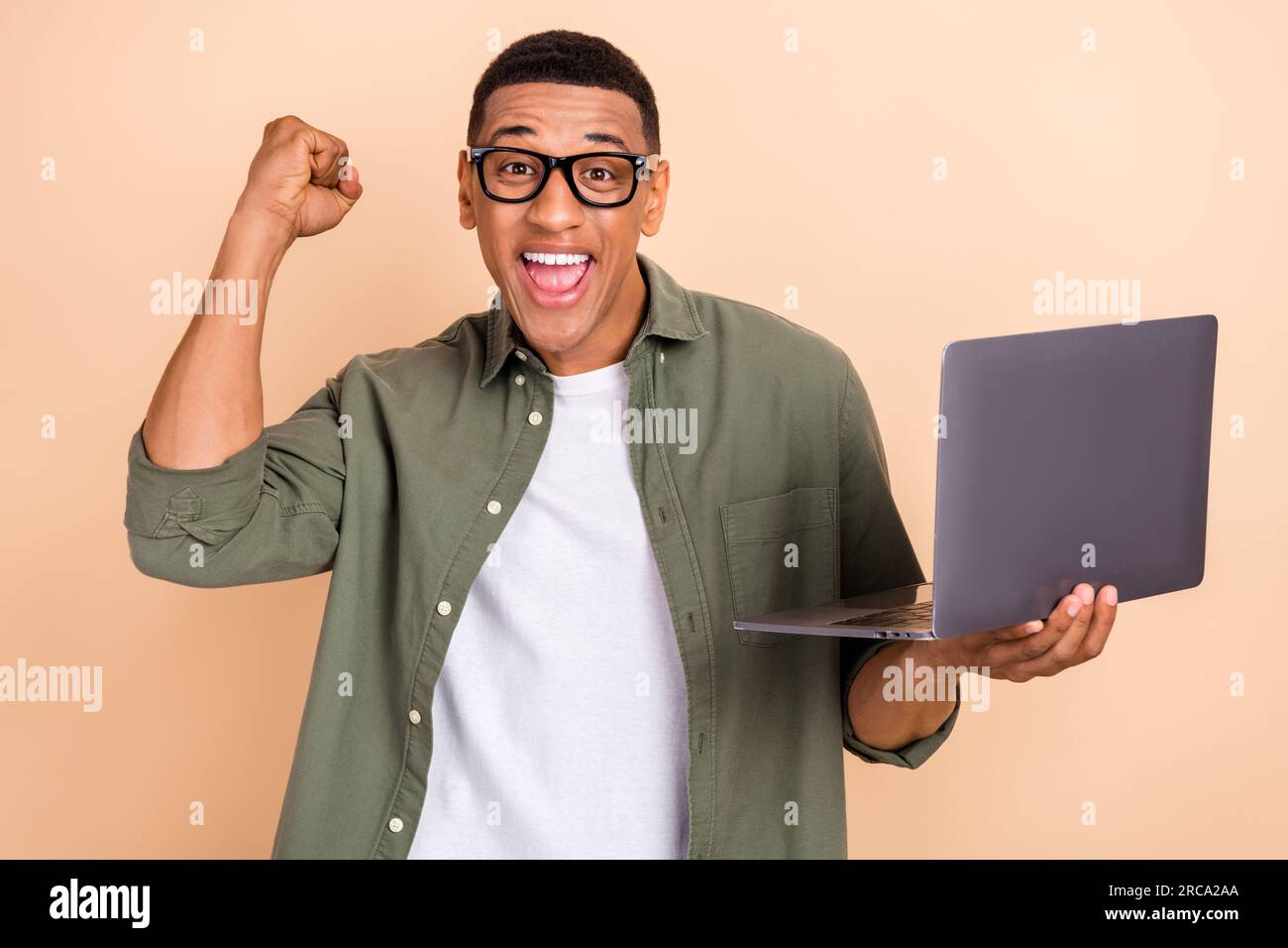Photo of delighted positive guy hold use netbook raise fist achievement ...