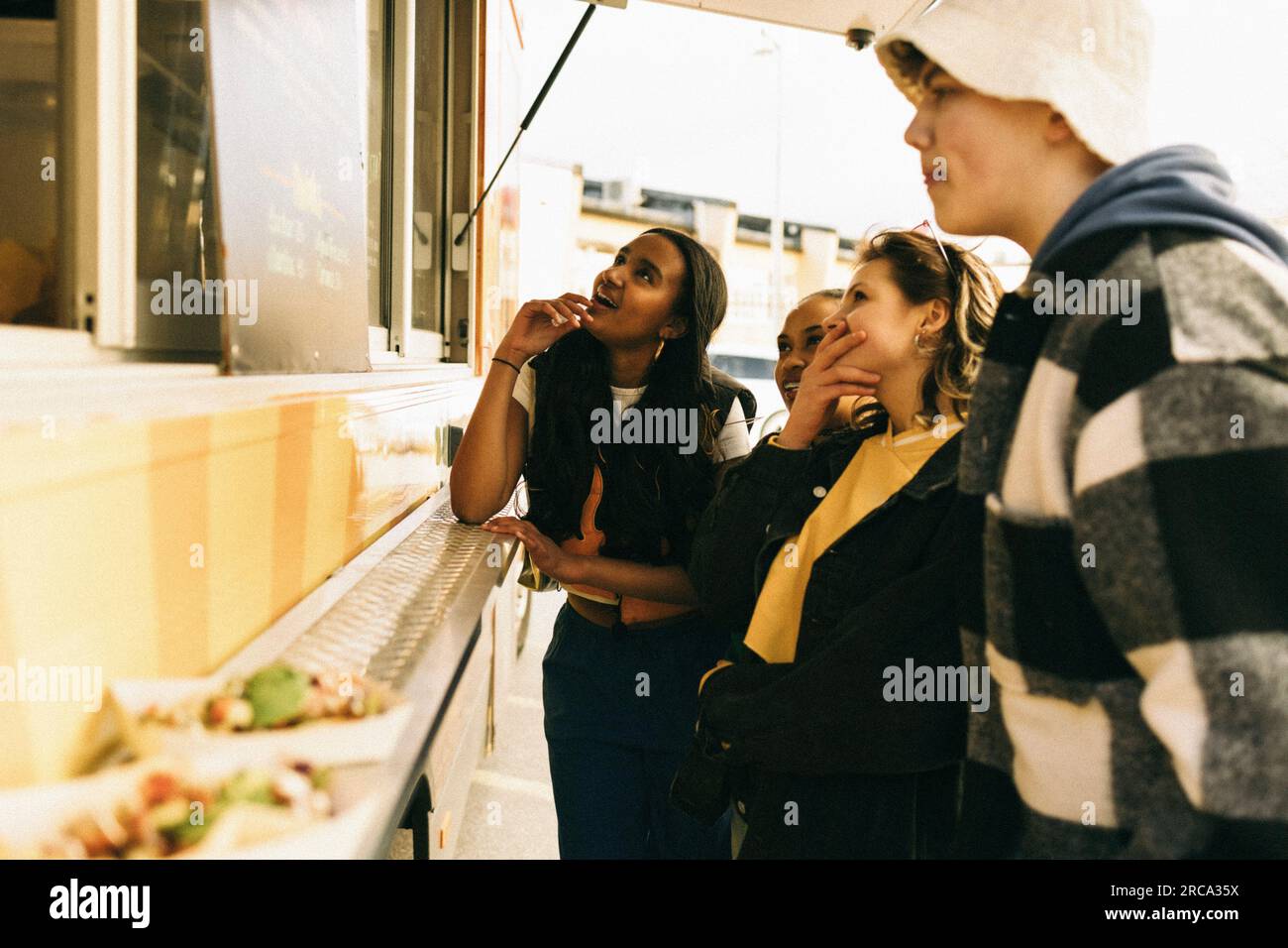 Male and female friends choosing food from menu while standing near ...