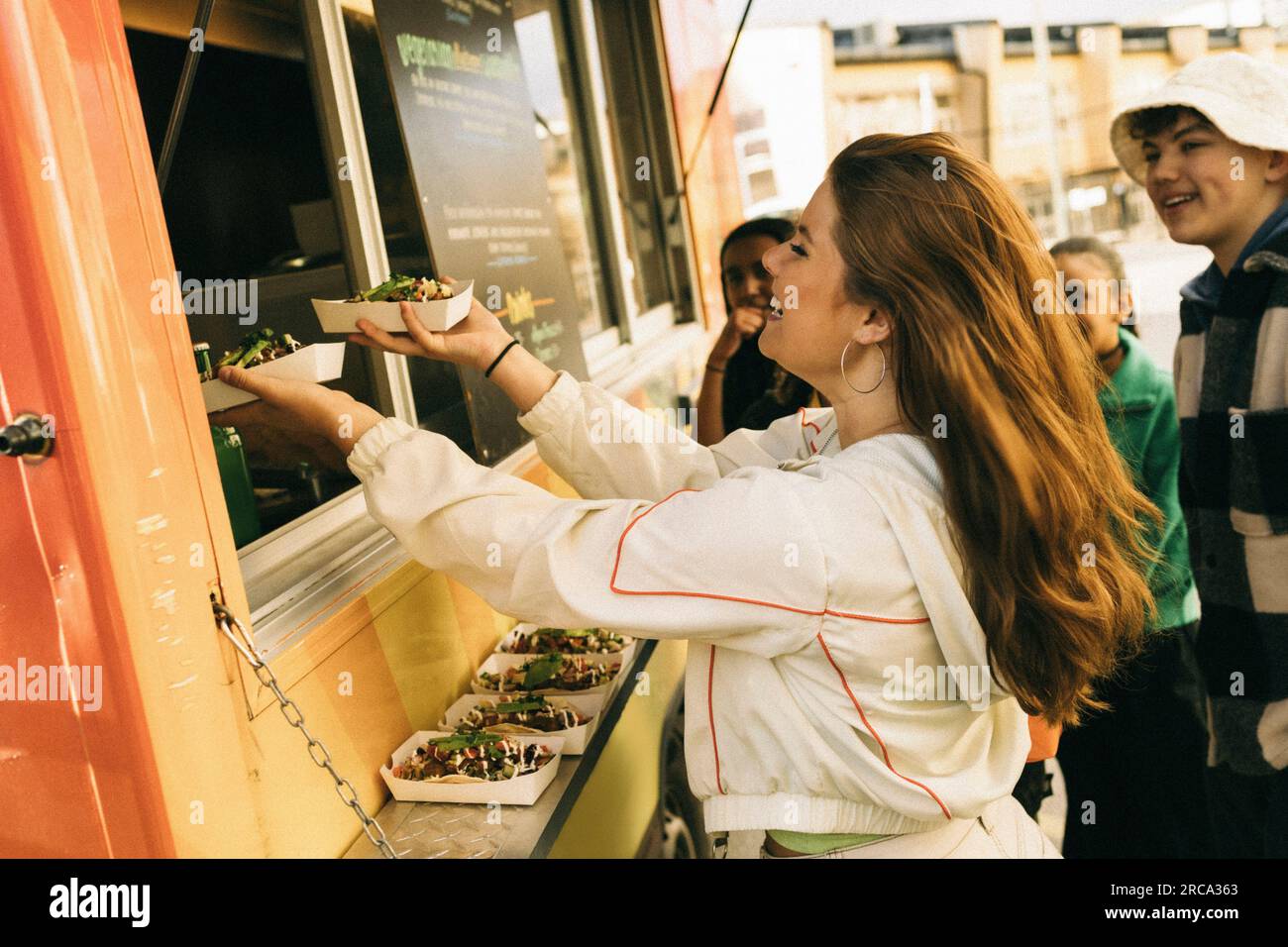 Side view of happy woman taking food from concession stand Stock Photo ...