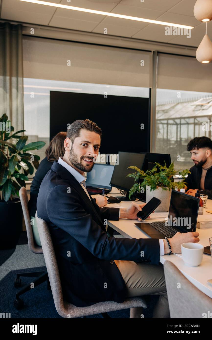 Side view portrait of businessman sitting on chair at desk in coworking ...