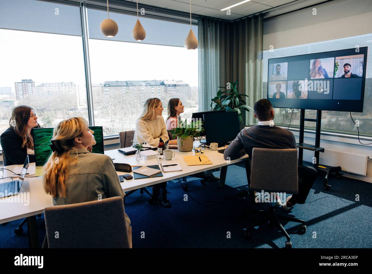 Male and female business colleagues looking at TV screen with video ...