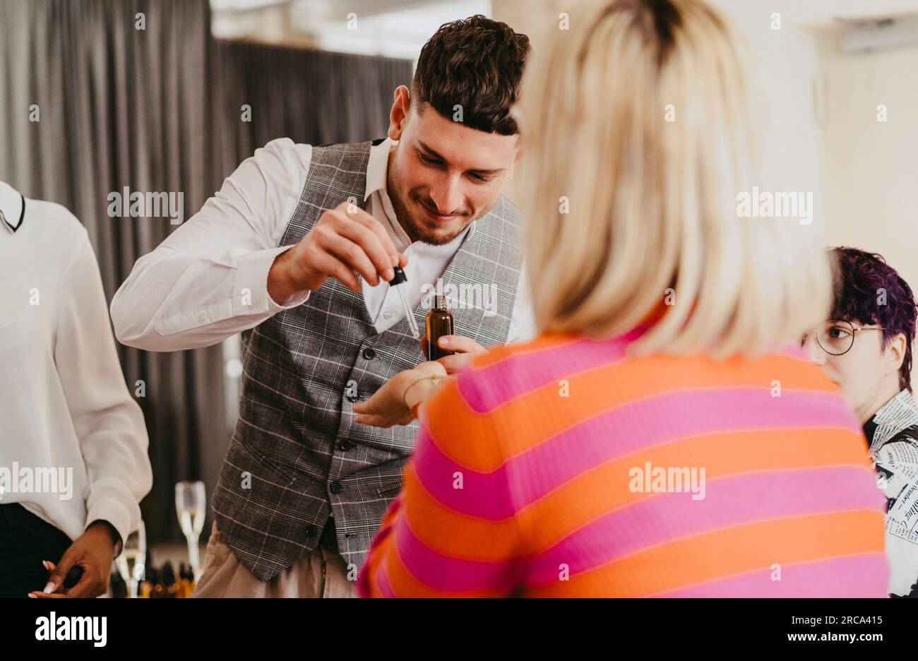 Smiling businessman giving sample of essential oil to colleague during ...