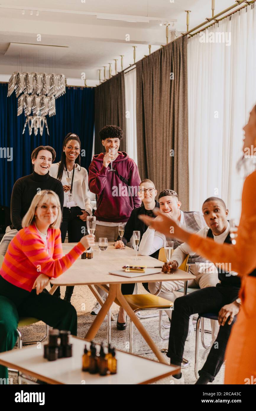 Male and female business colleagues listening to speech during event at ...