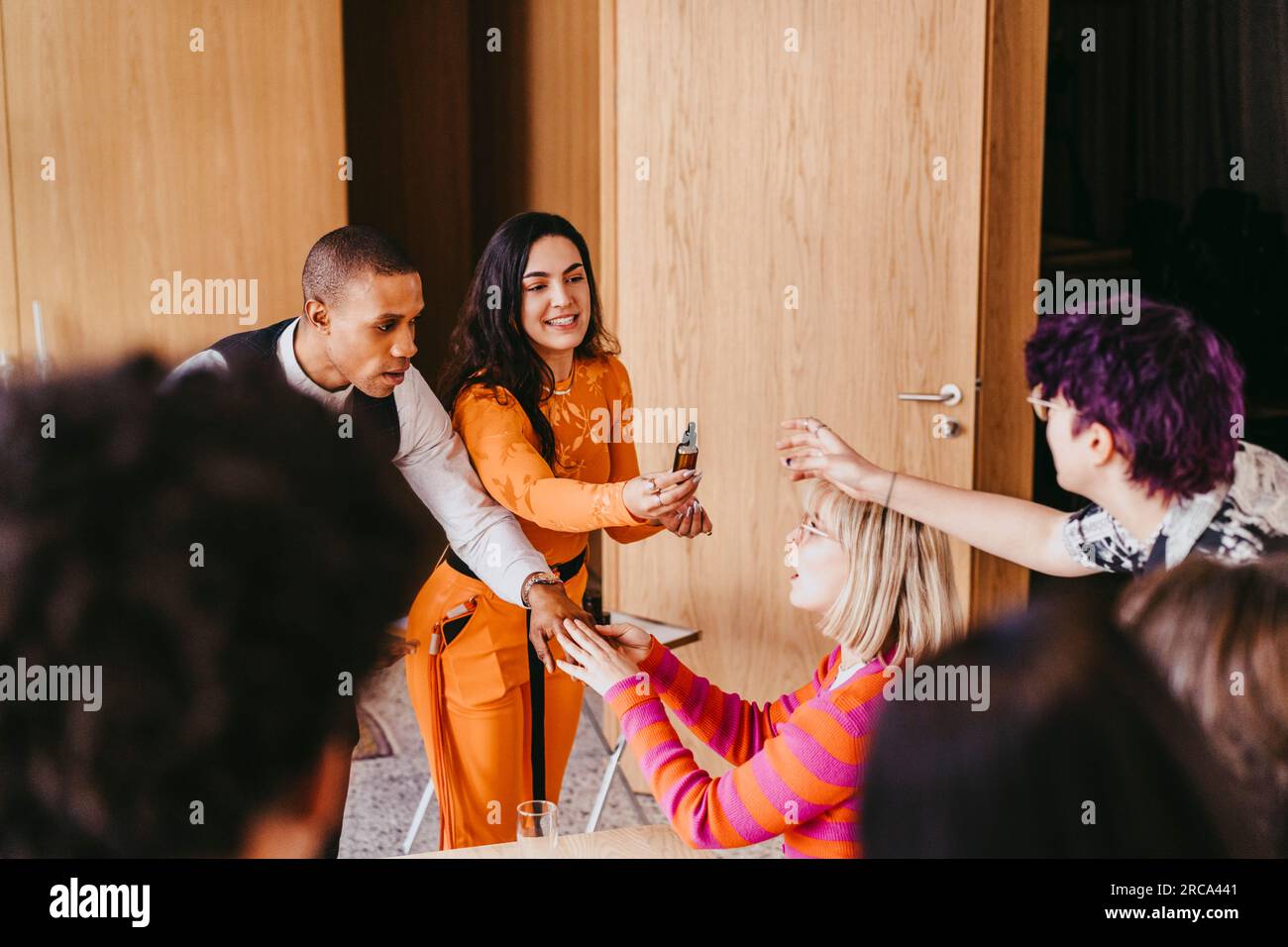 Businesswoman distributing essential oil samples to colleagues during ...