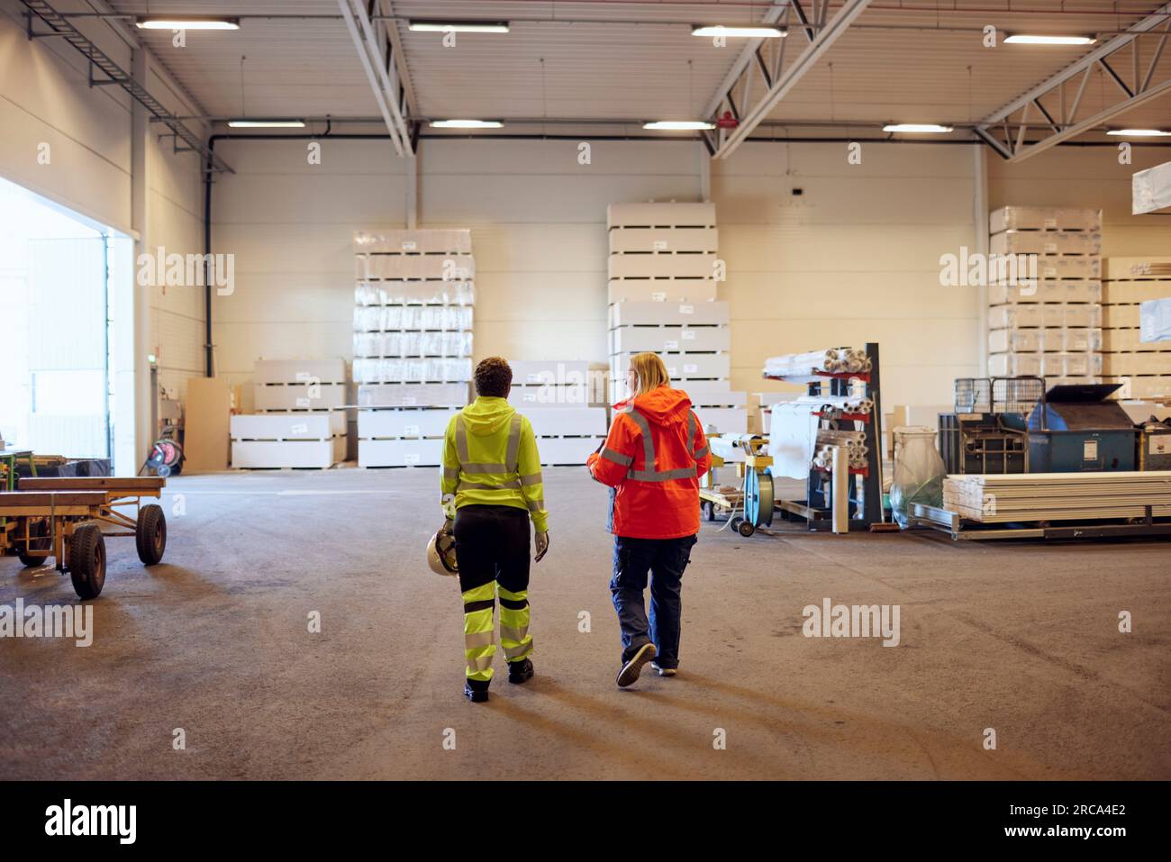 Rear view of multiracial female colleagues walking in distribution ...