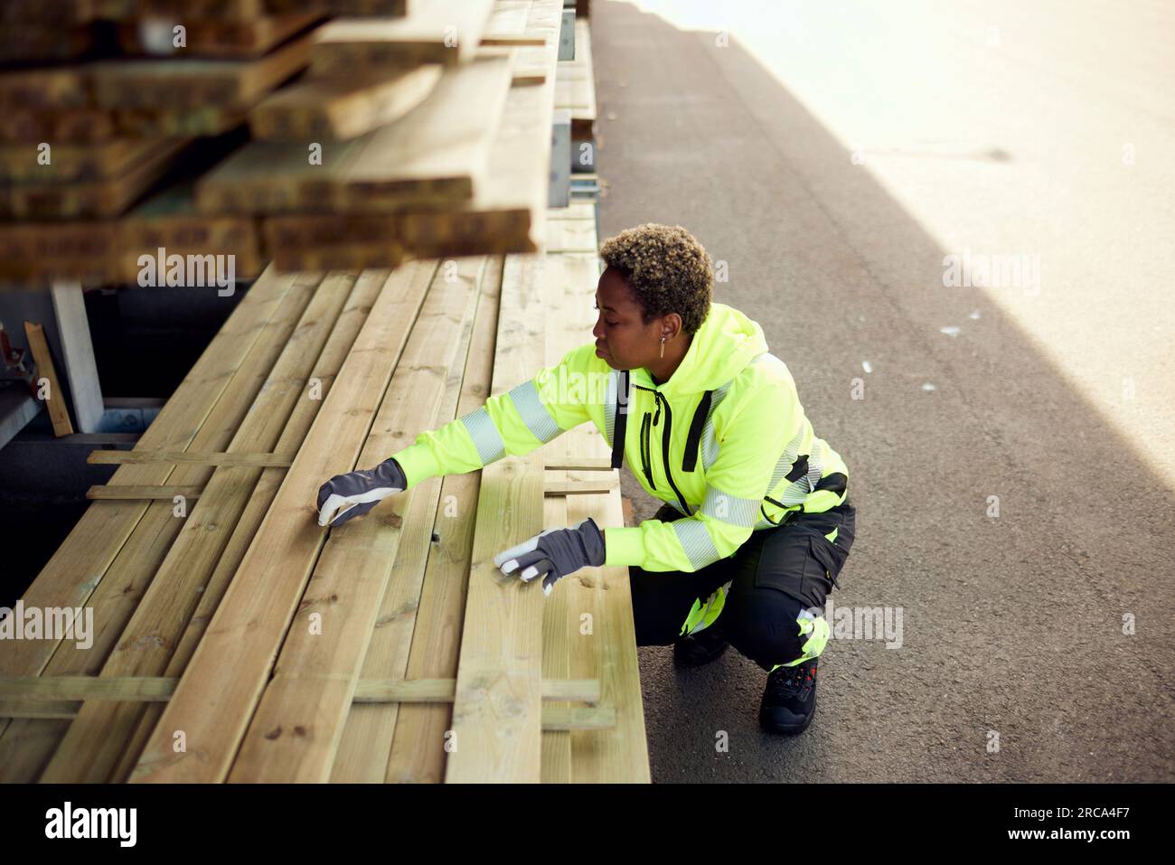 Full length of young female worker arranging planks at lumber industry ...