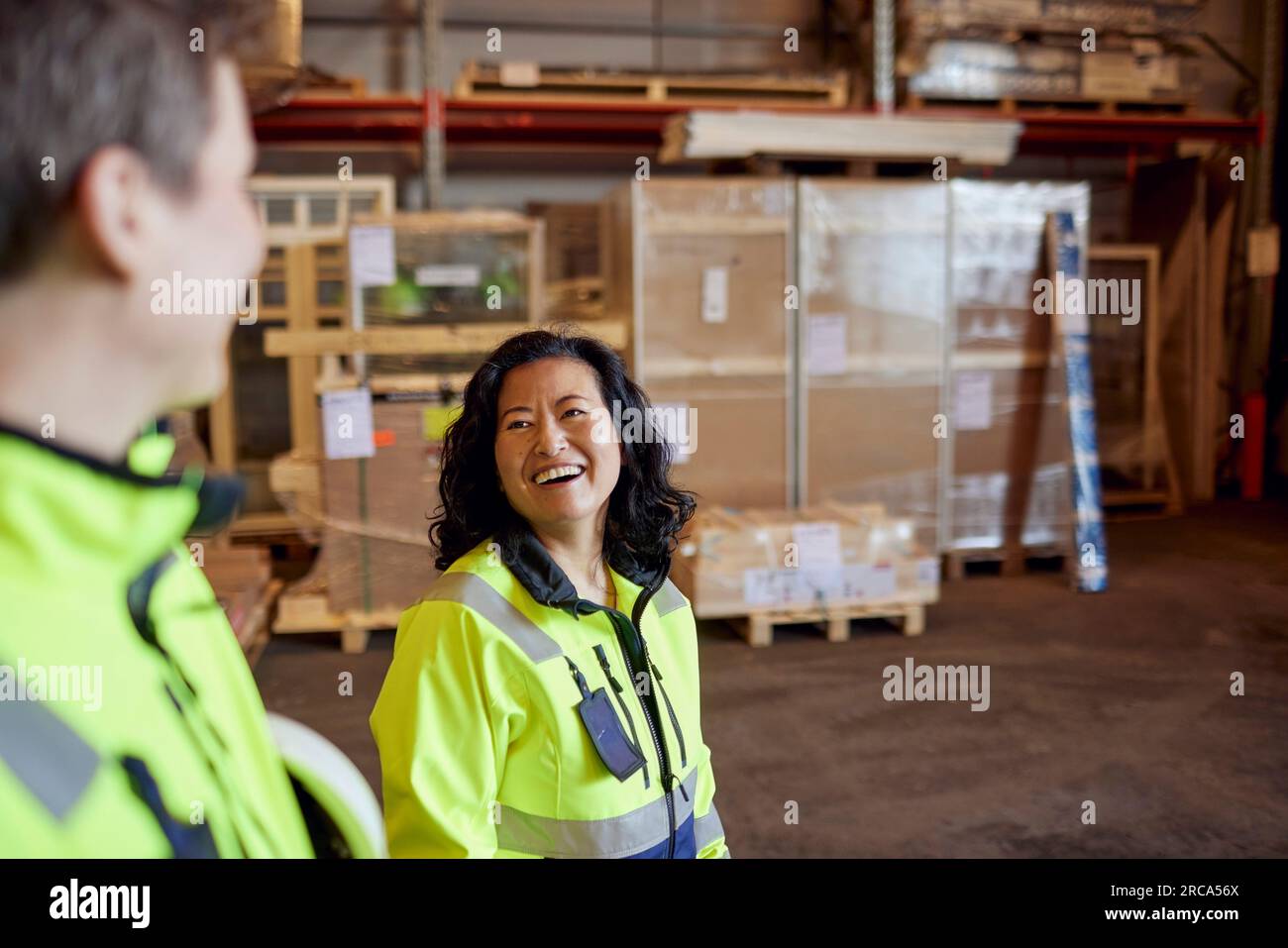 Happy female worker discussing with colleague while walking in ...