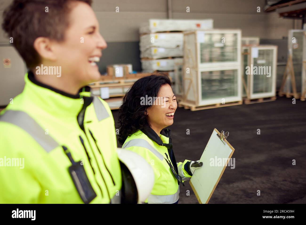 Happy multiracial female colleagues walking in distribution warehouse ...