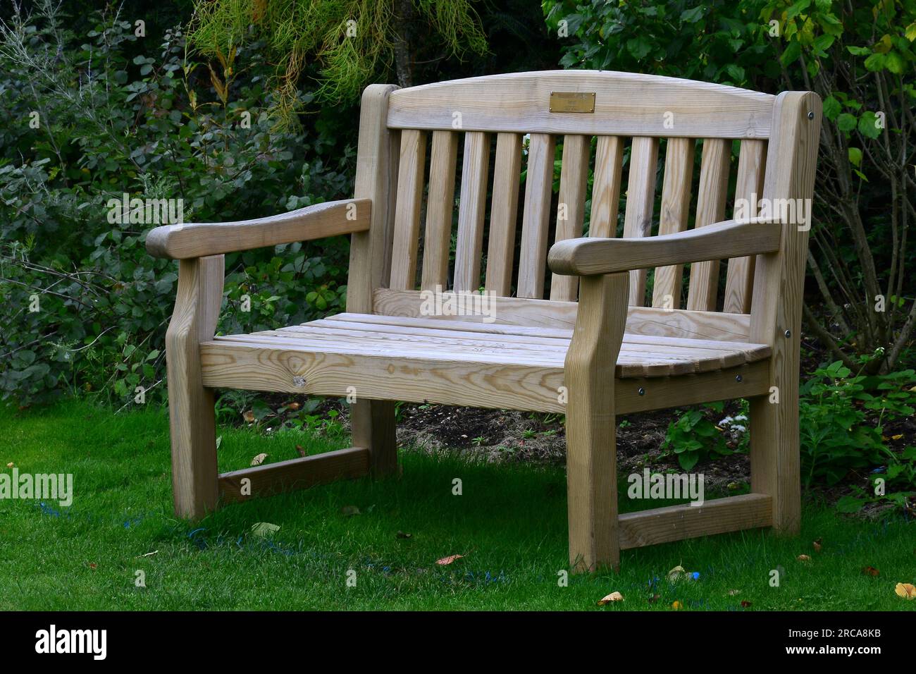 Two-seater wooden bench with arms Stock Photo - Alamy
