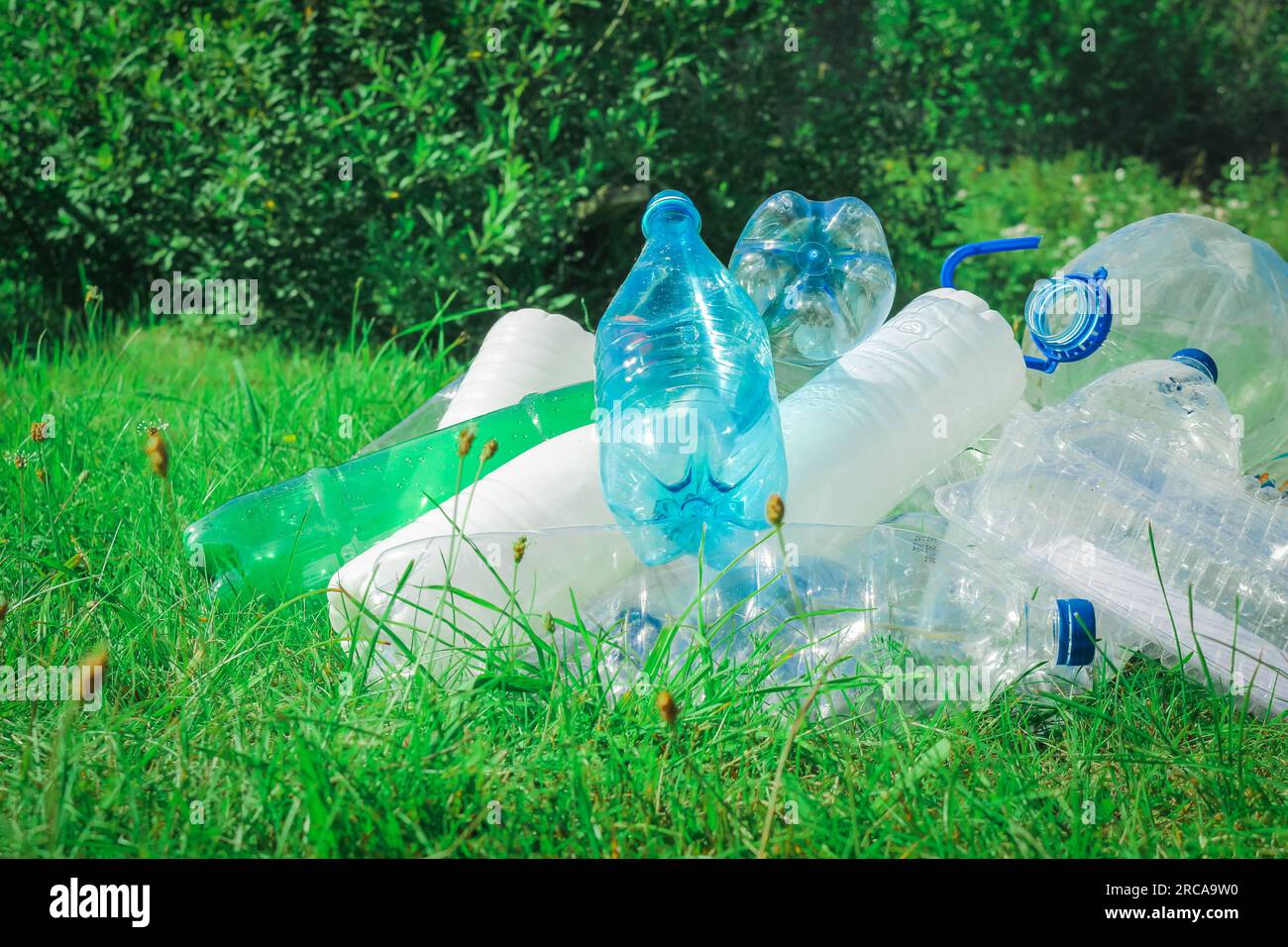 Plastic bottles and bottle caps on grass in park, littering of ...