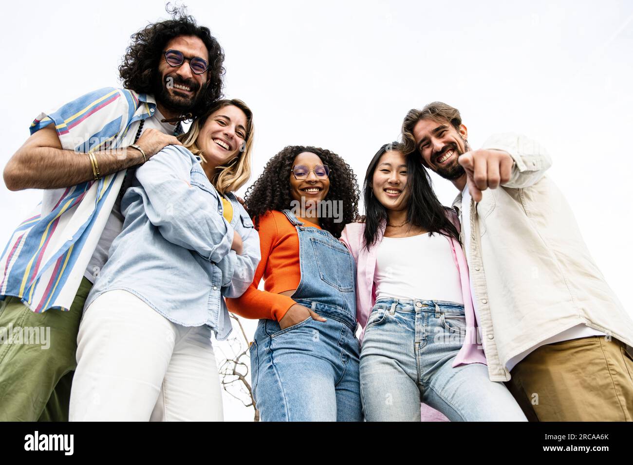 Low view of confident multiracial group of young hipsters laughing and ...