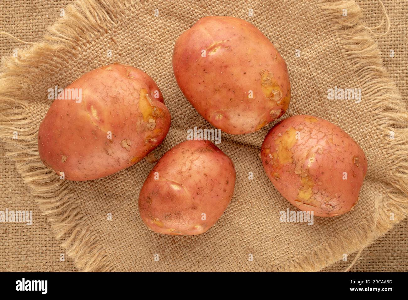 Four raw pink potatoes on jute cloth, top view Stock Photo - Alamy