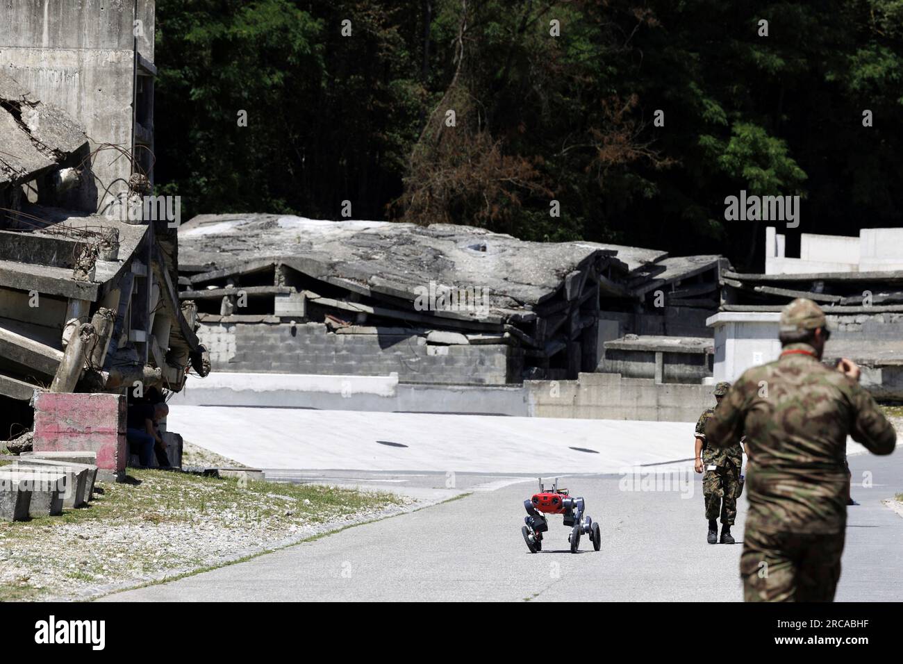 Swiss soldiers walk next to a four-wheeled robot by Swiss-Mile, a spin ...