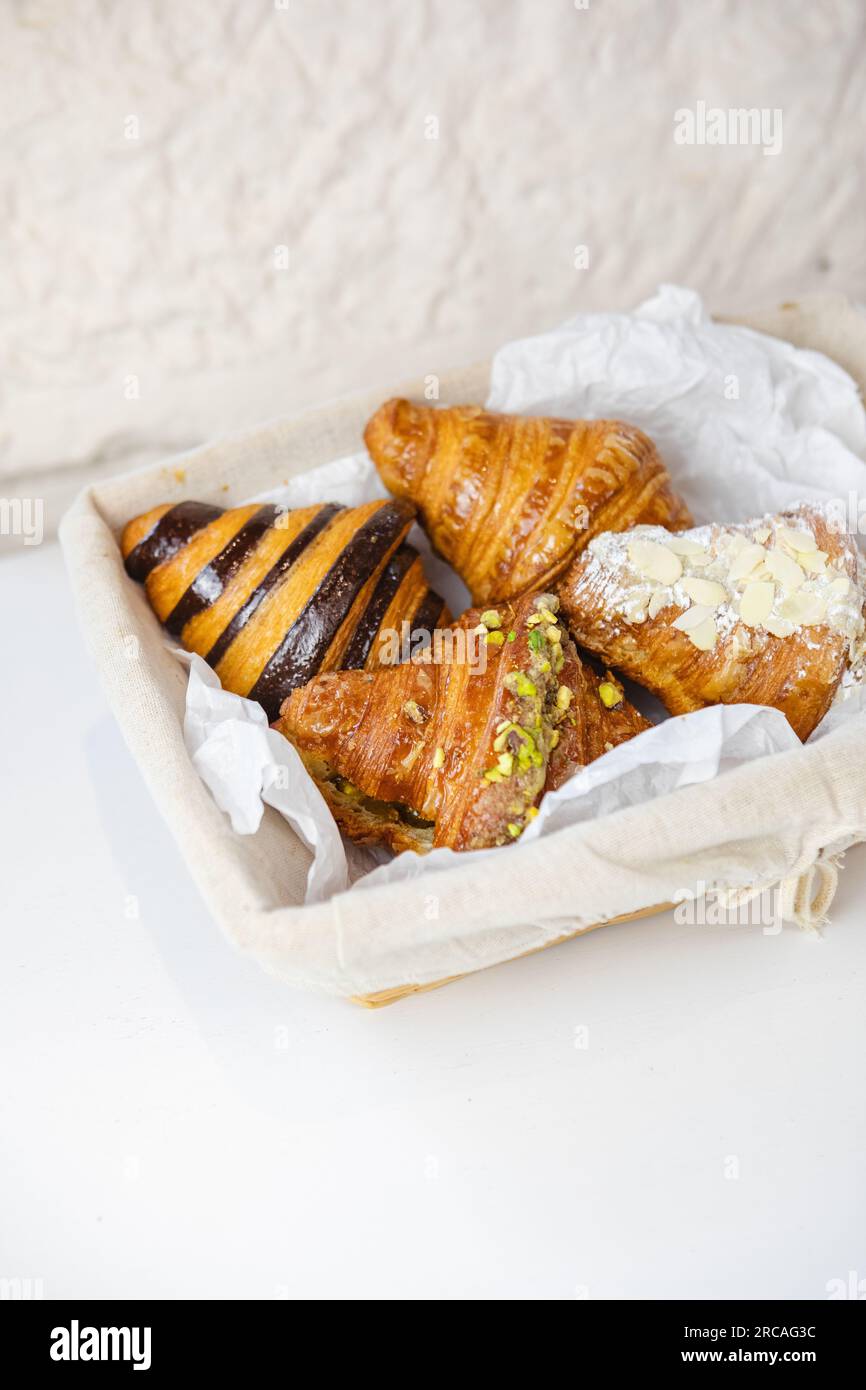 four types of croissants in a basket on a white table Stock Photo - Alamy