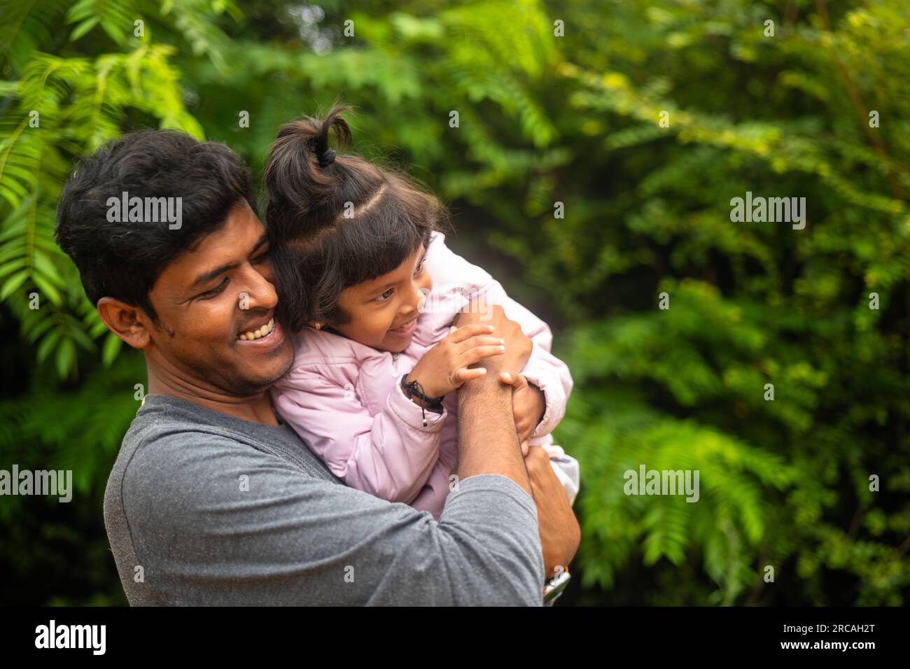 A loving Indian father and daughter are smiling and enjoying a sunny ...
