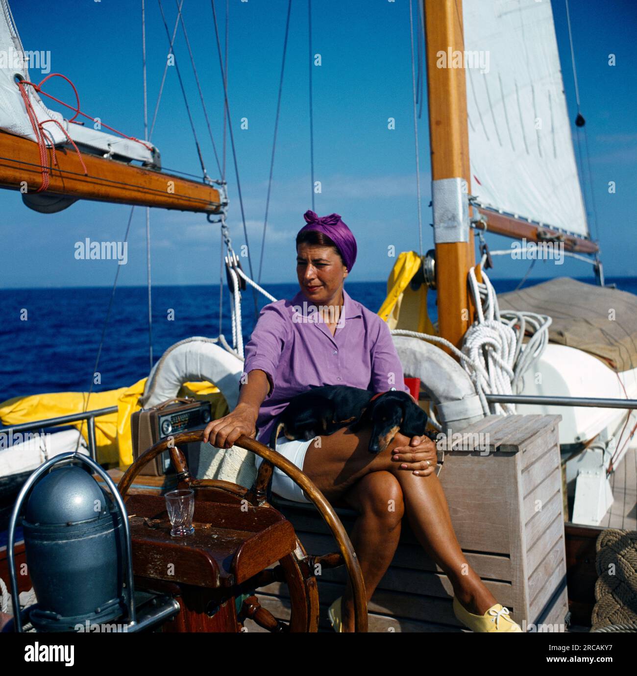 Woman at the Helm of Sailing Yacht With Dachshund Dog on Lap Stock ...