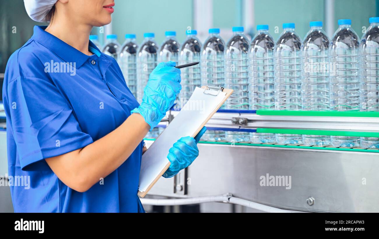 Bottling factory worker inspecting quality of water bottles before shipment. Reverse osmosis ...