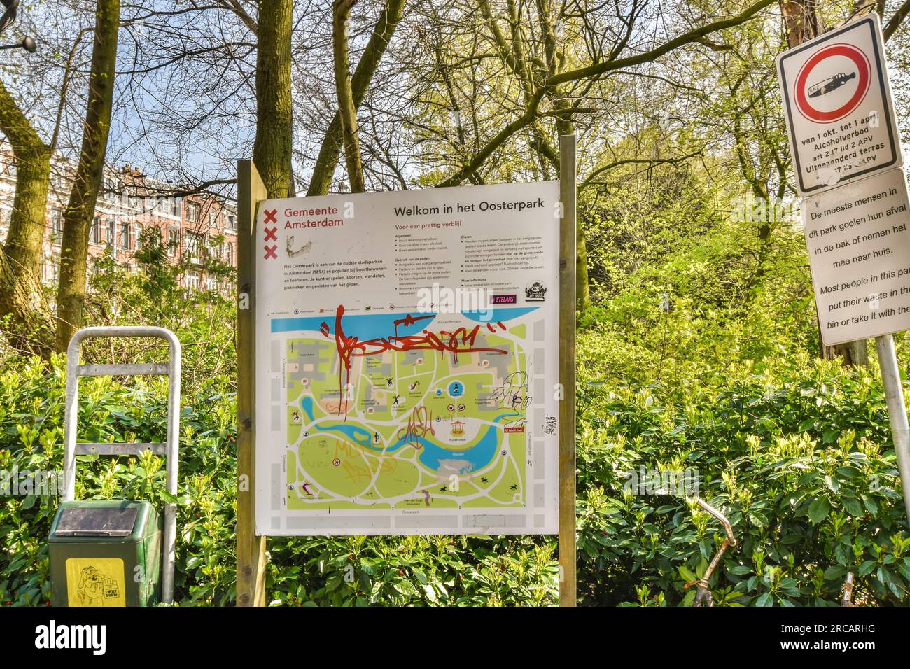 some signs in the middle of a park with trees and bushes on either ...