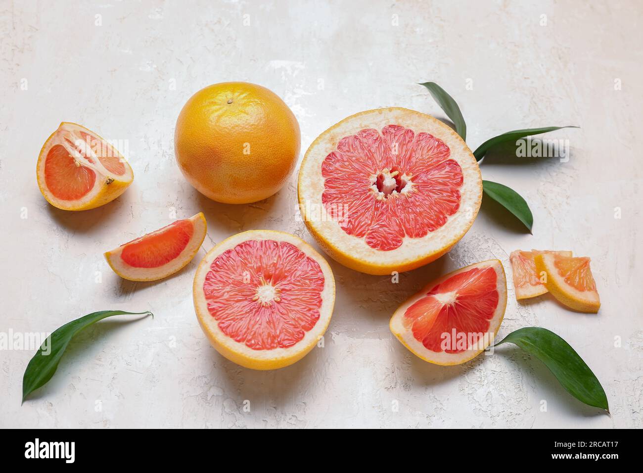 Composition with juicy grapefruit pieces and plant leaves on light ...