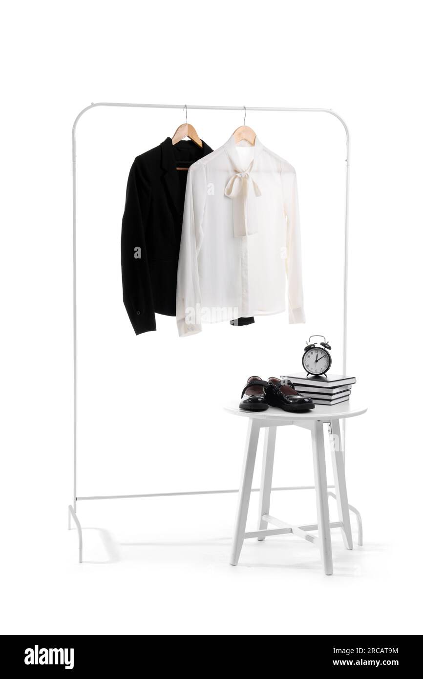 Rack with stylish school uniform, chair, books, alarm clock and shoes ...