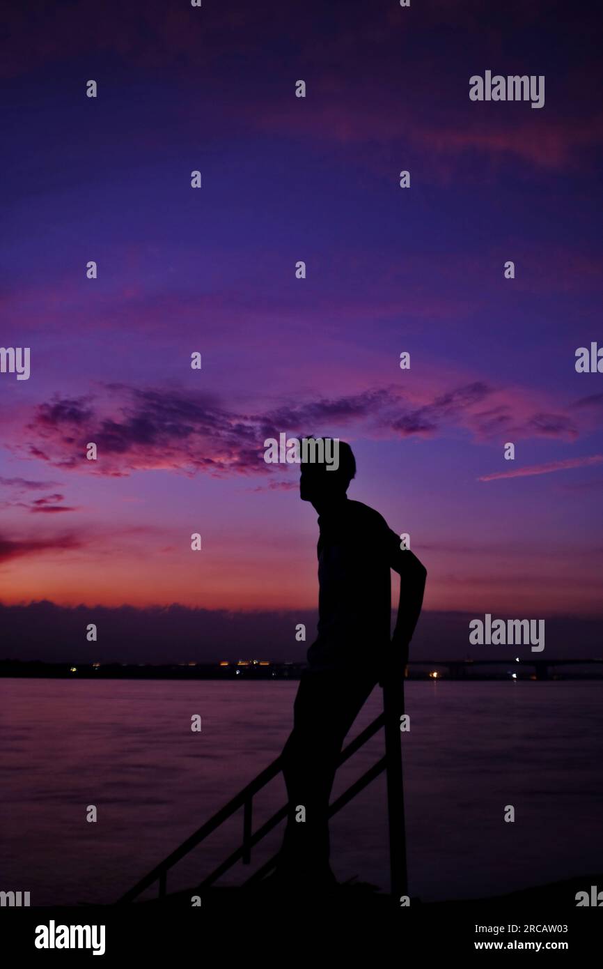 a man watching sunrise down by the river Stock Photo - Alamy