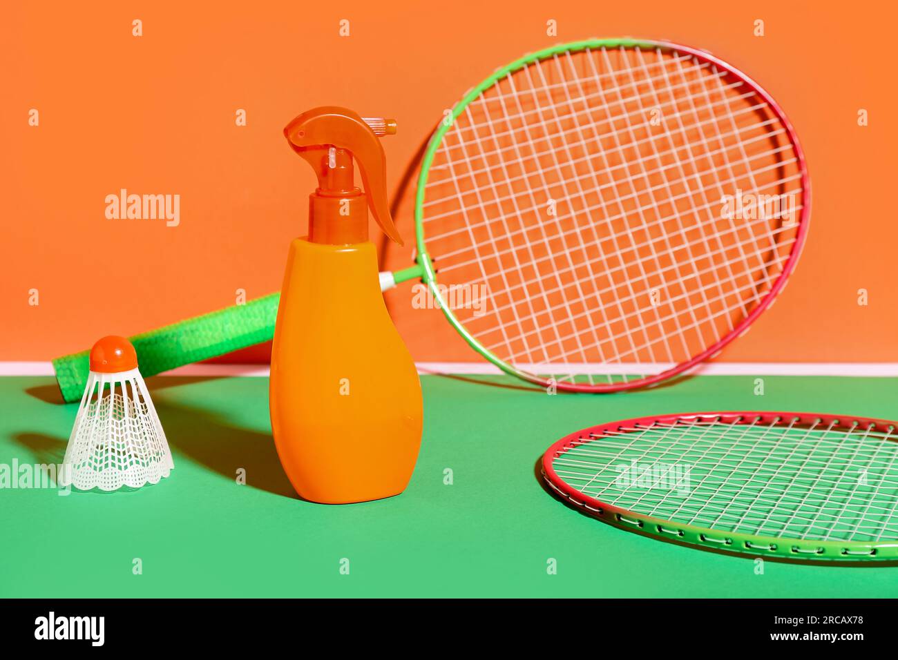 Bottle of sunscreen cream, badminton rackets and shuttlecock on color ...
