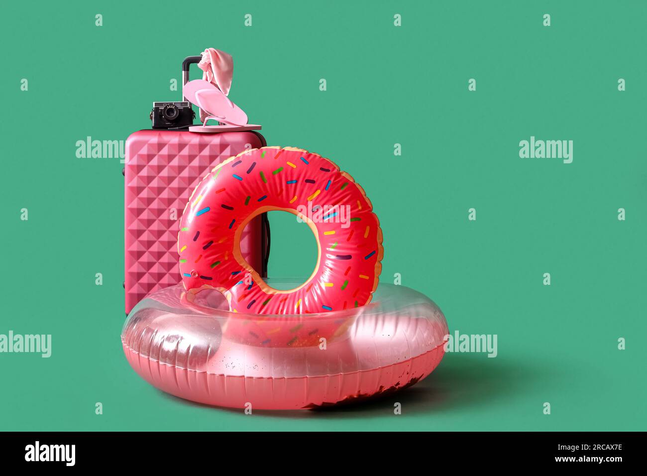 Suitcase with inflatable rings, flip flops and camera on turquoise ...
