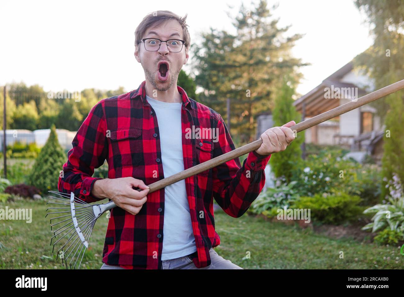 Gardener or farmer man holding rake like a guitar. Working in garden ...
