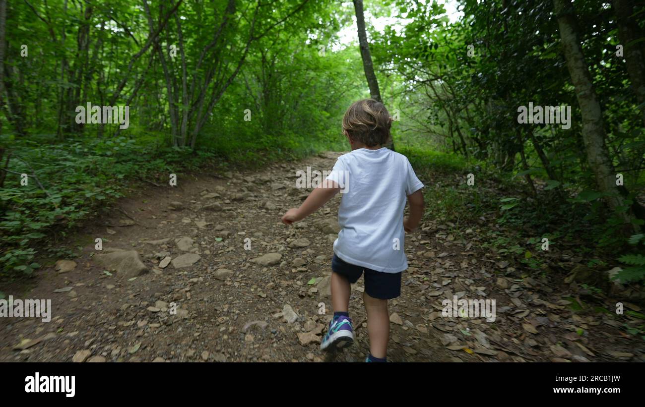 Small boy hiking going up hill outside in nature child stepping on ...