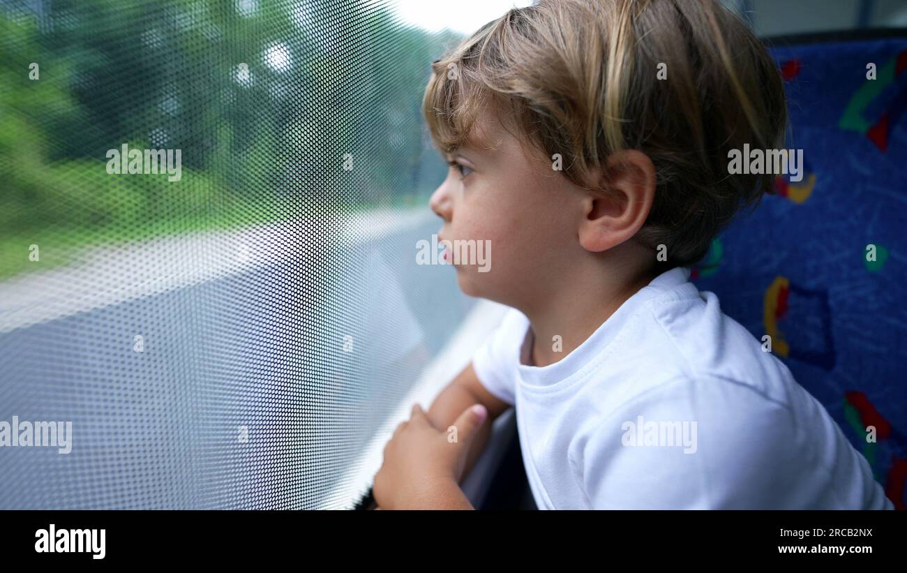 One passenger little boy traveling by bus looking out vehicle window ...