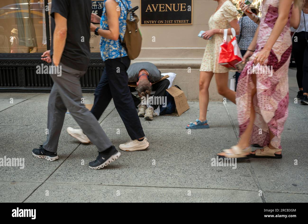 People walk past a homeless man begging on the sidewalk in the Flatiron ...