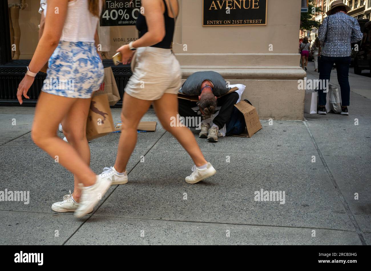 People walk past a homeless man begging on the sidewalk in the Flatiron ...