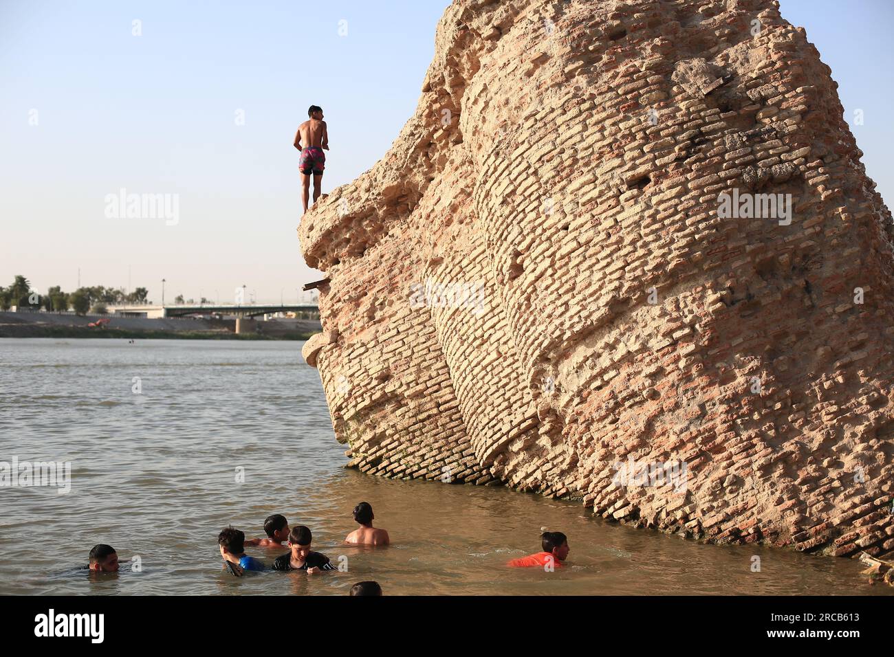 Baghdad, Iraq. 13th July, 2023. Iraqi boys swim in the water of the ...
