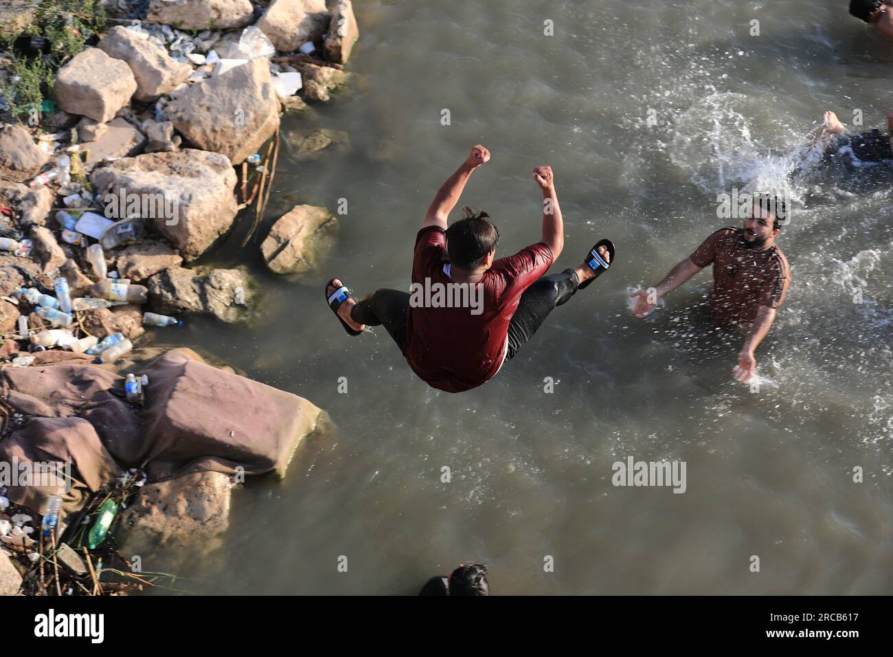 Baghdad, Iraq. 13th July, 2023. An Iraqi man dives into the water of ...