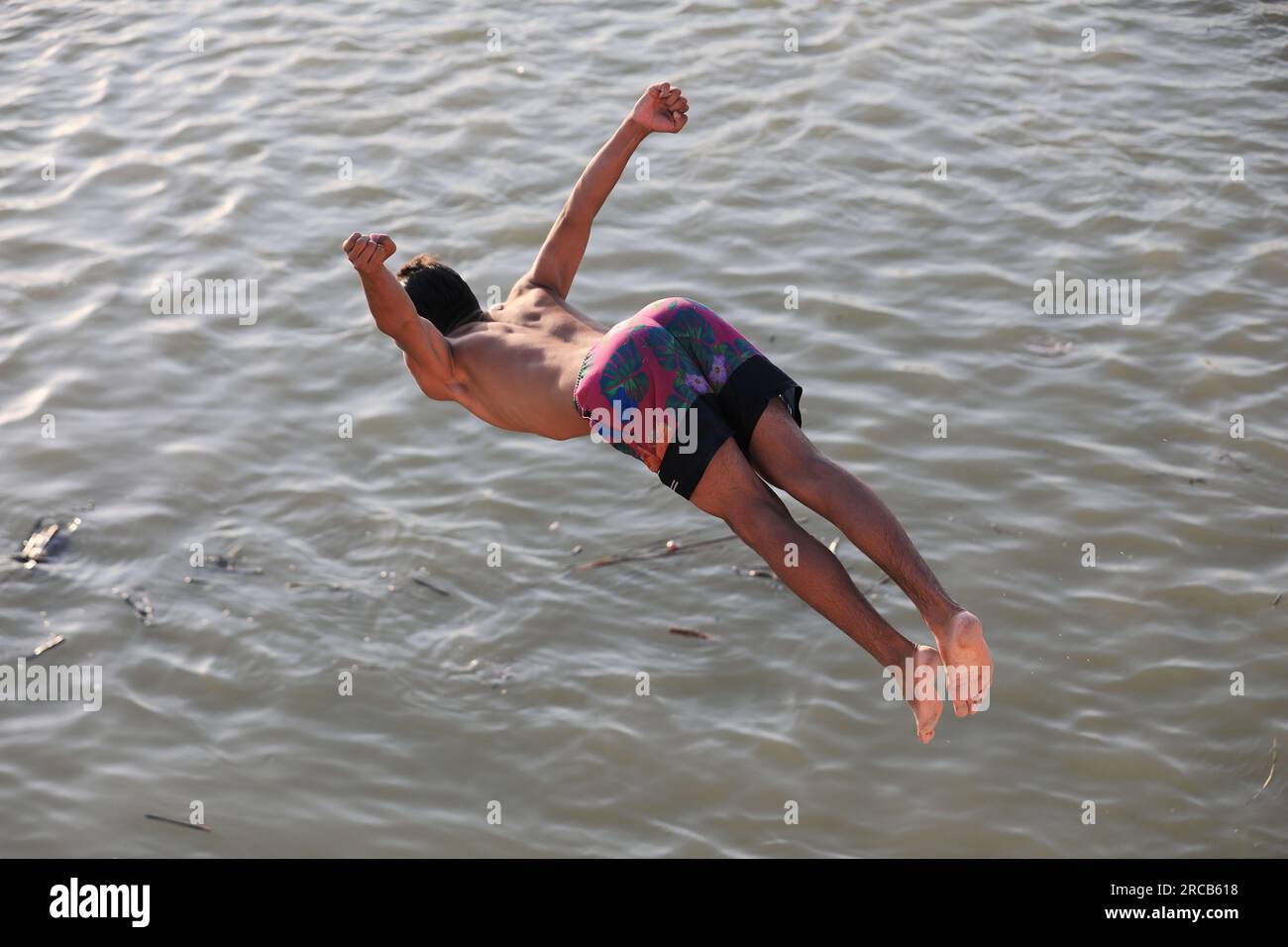 Baghdad, Iraq. 13th July, 2023. An Iraqi boy dives into the water of ...