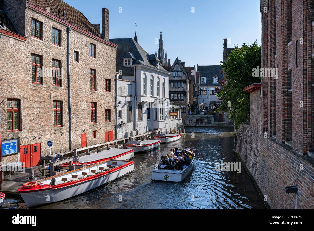 Canal ride between medieval buildings in the old town of Bruges ...