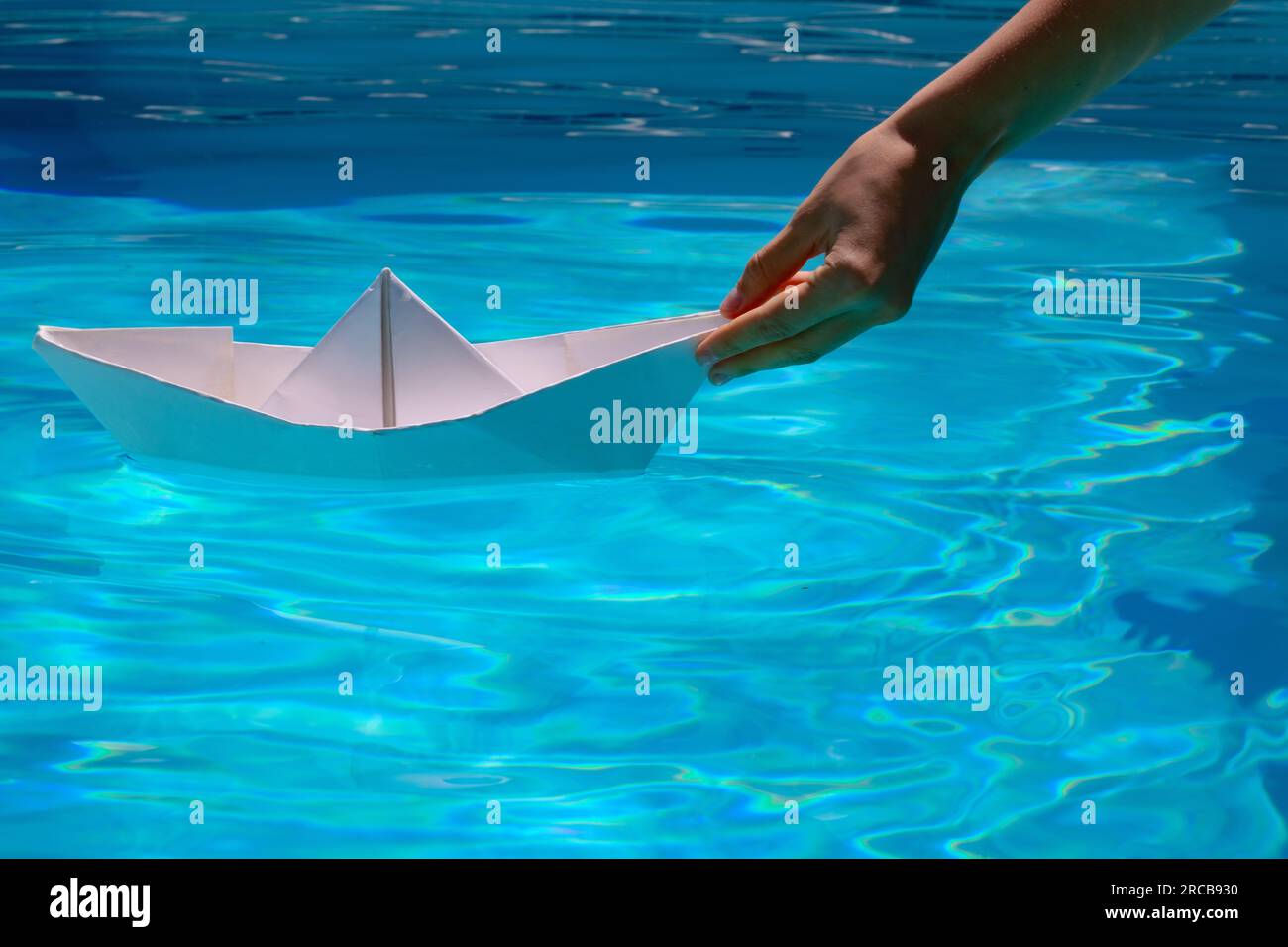 Female hand holding paper boat on the sea background. Tourism and ...