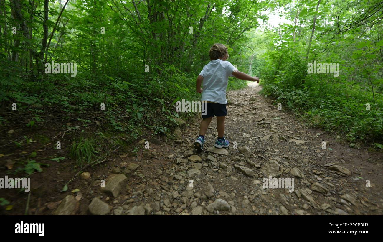 Child hiking outside on green path kid walking outdoors in the woods ...