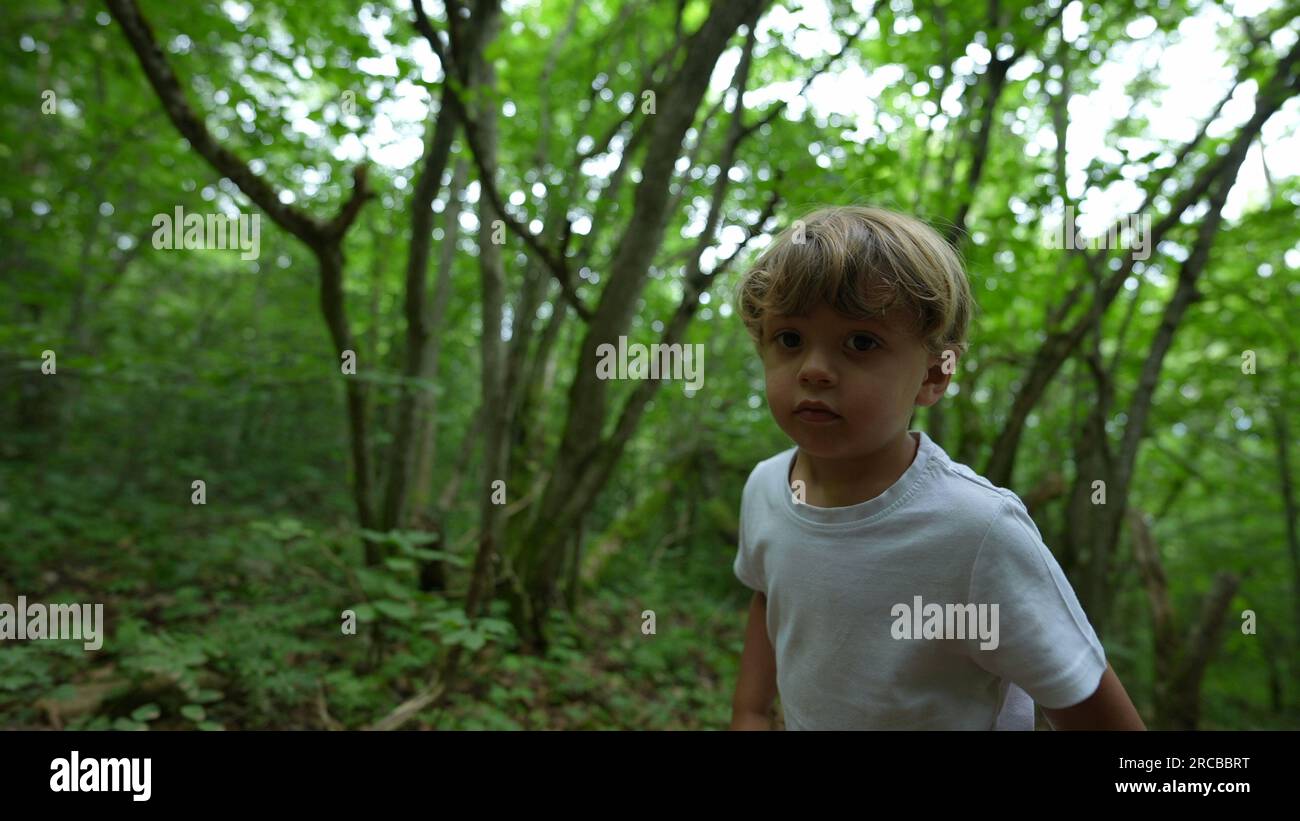 Child hiking outside on green path kid walking outdoors in the woods ...