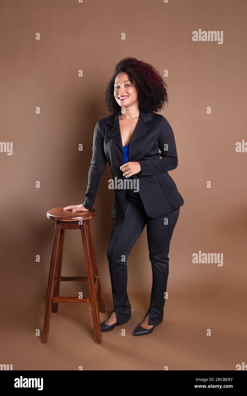 Young manager, elegant and beautiful, leaning on a wooden stool ...