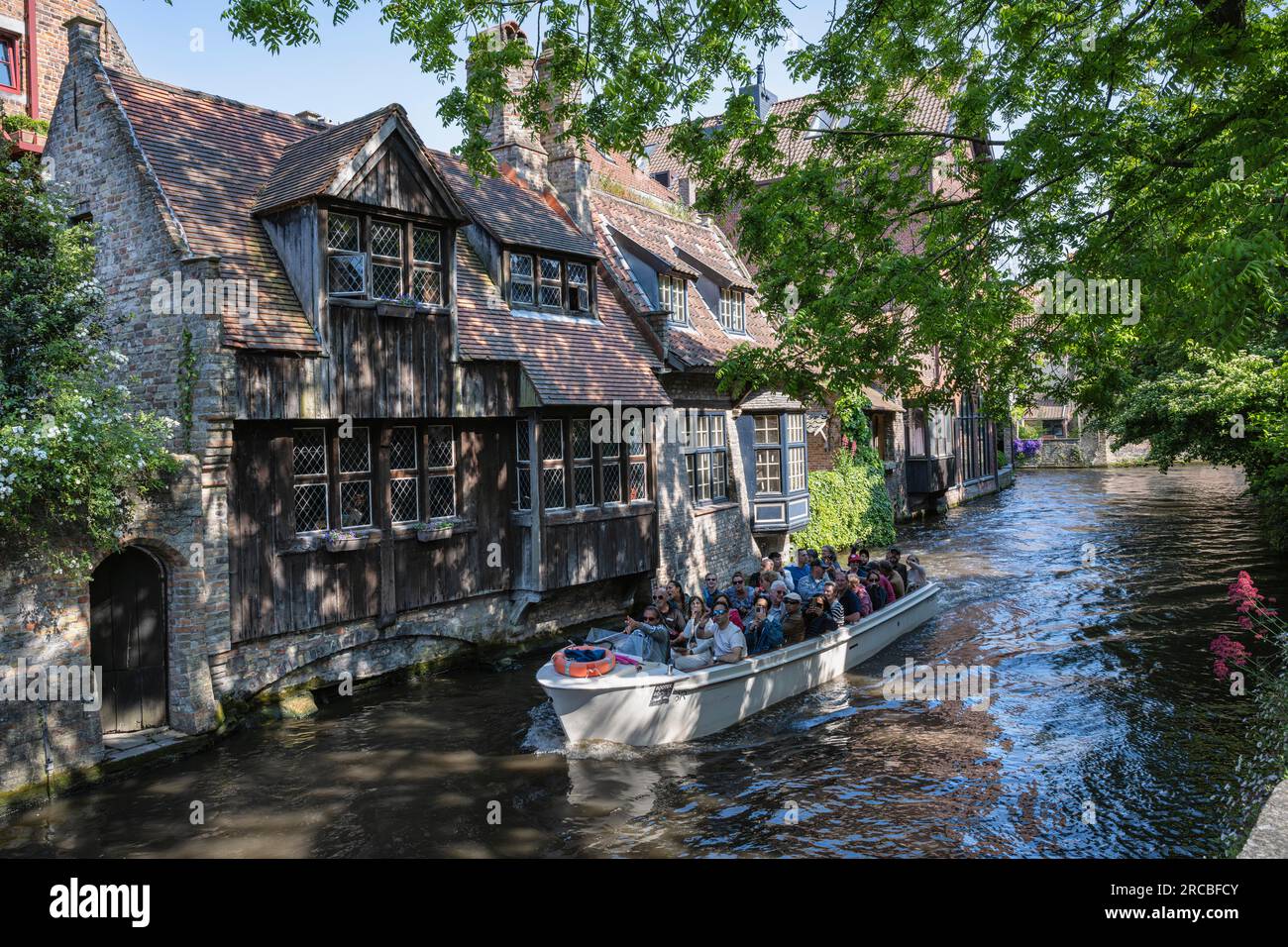 Canal ride between medieval buildings in the old town of Bruges ...