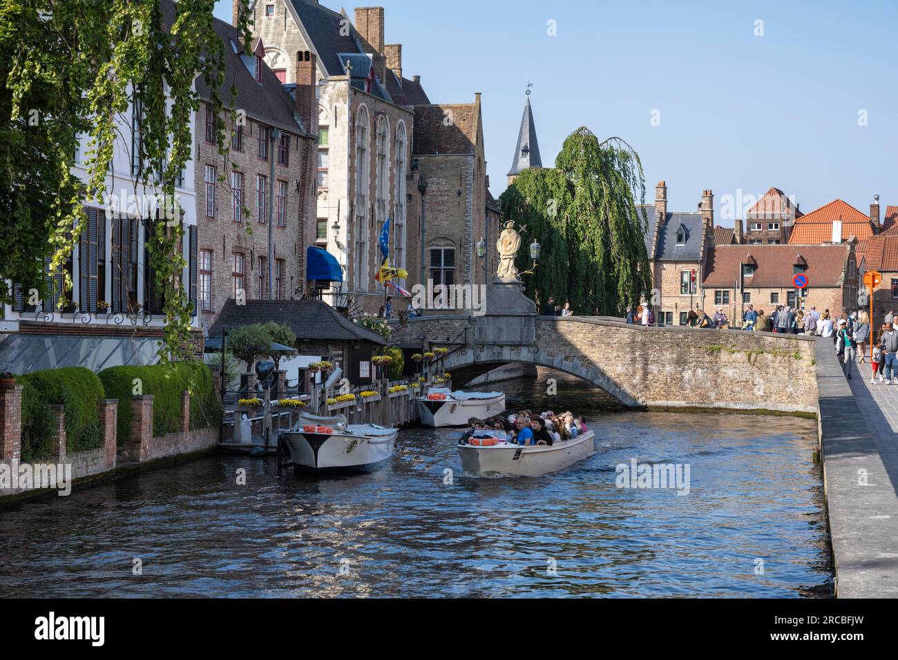 Canal ride between medieval buildings in the old town of Bruges ...