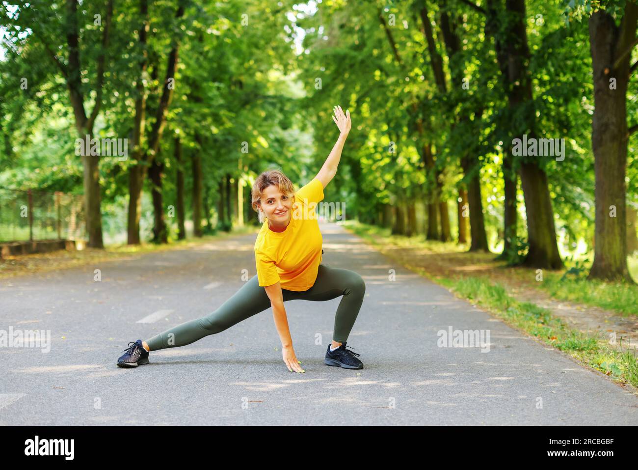 Smiley Caucasian Young Woman Makes Stretching Exercise At Park Smiles
