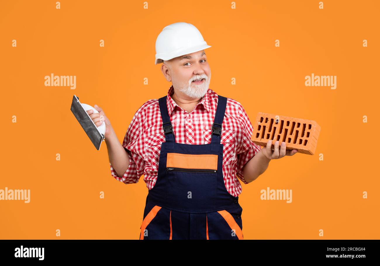 happy old man bricklayer in helmet on yellow background Stock Photo - Alamy