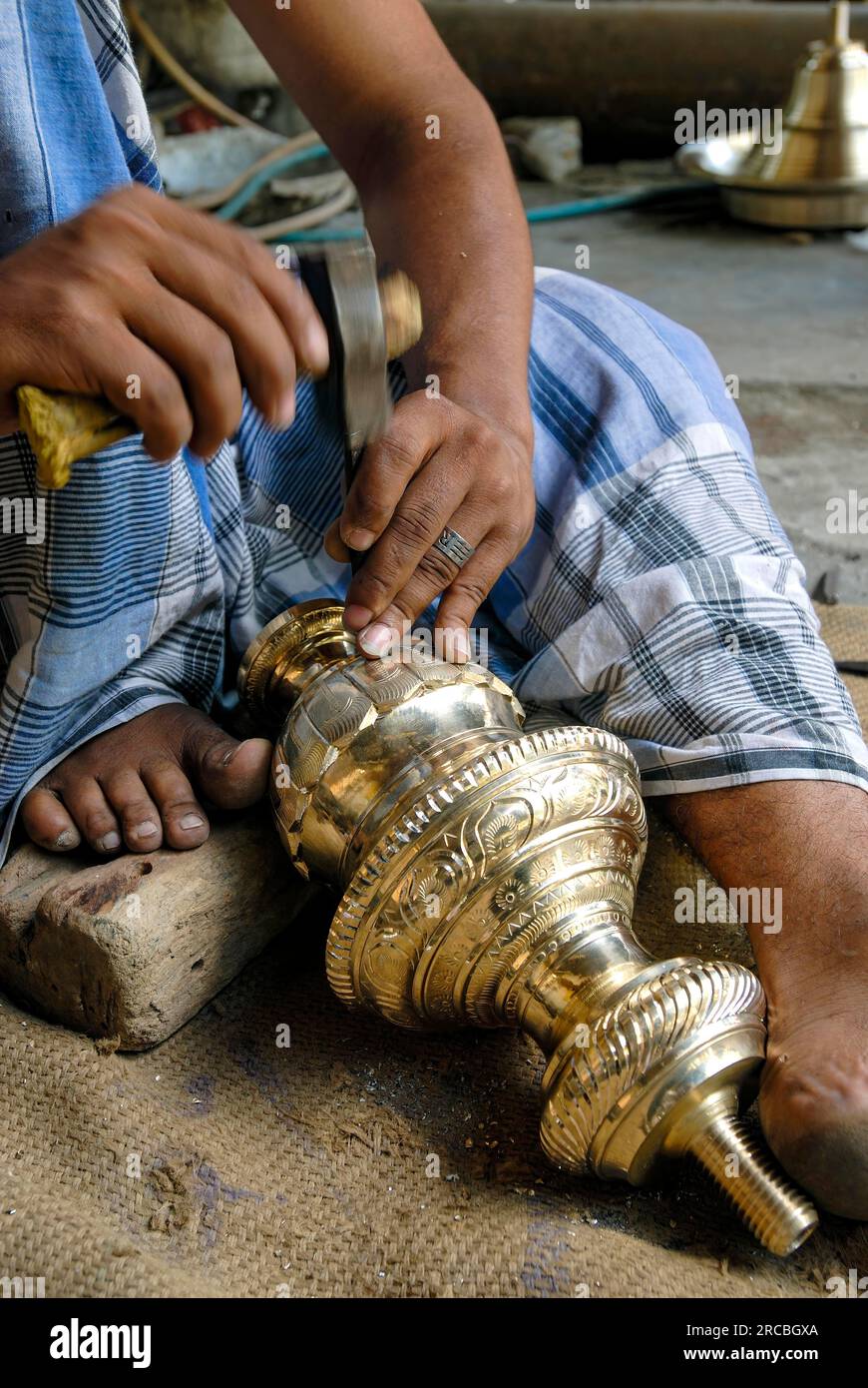 An artisan working carving on brass lamp at NachiyarKoil Nachiyar Koil ...