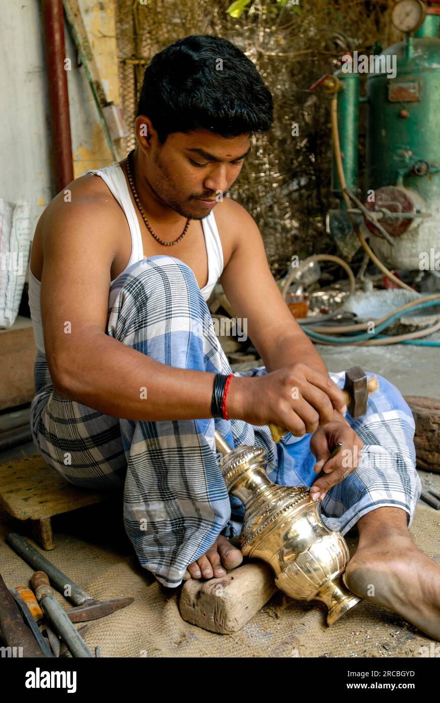An artisan working carving on brass lamp at NachiyarKoil Nachiyar Koil ...