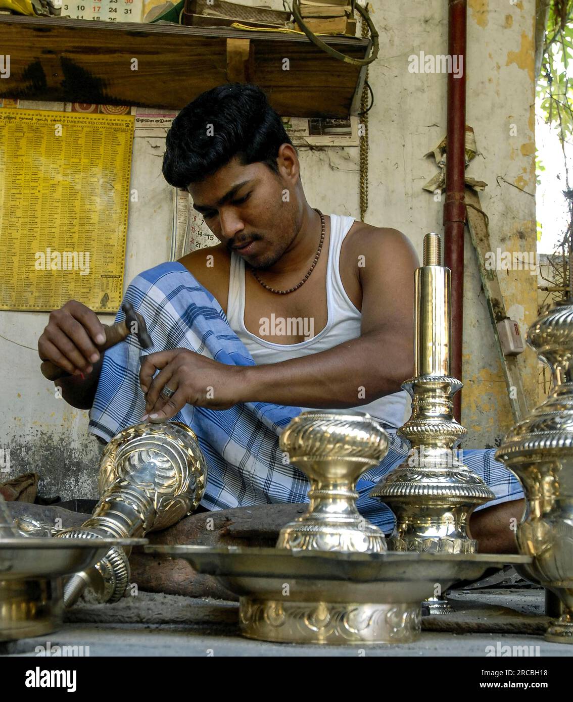 An artisan working carving on brass lamp at NachiyarKoil Nachiyar Koil ...