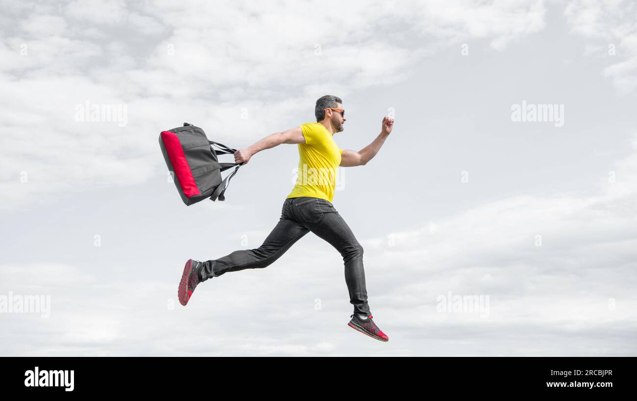 Active man running with sporty bag midair sky background, sport Stock ...